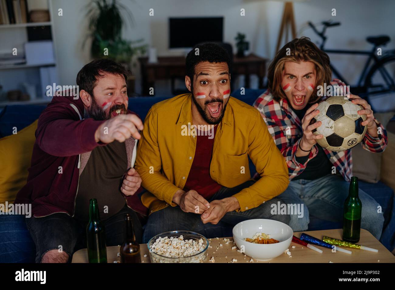 Nervous football fans friends watching live soccer match on TV at home ...