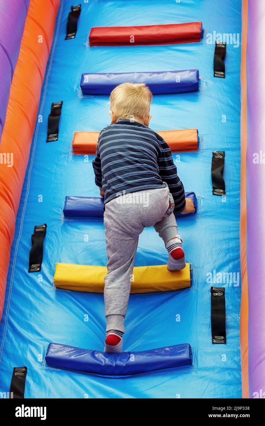 Brave little boy child climbs the stairs of a multi-colored slide in ...