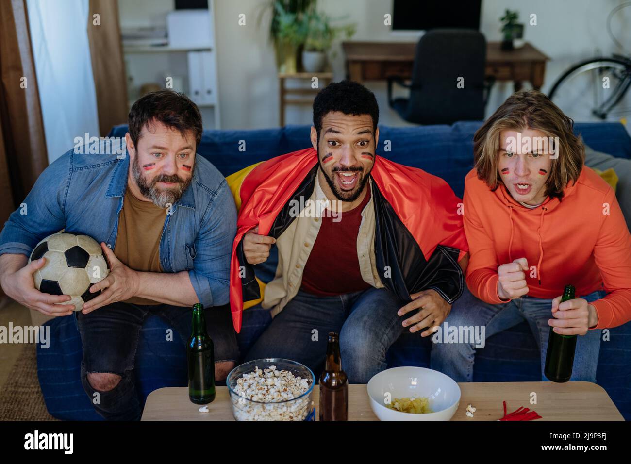 Nervous football fans friends staring at TV and watching football match ...