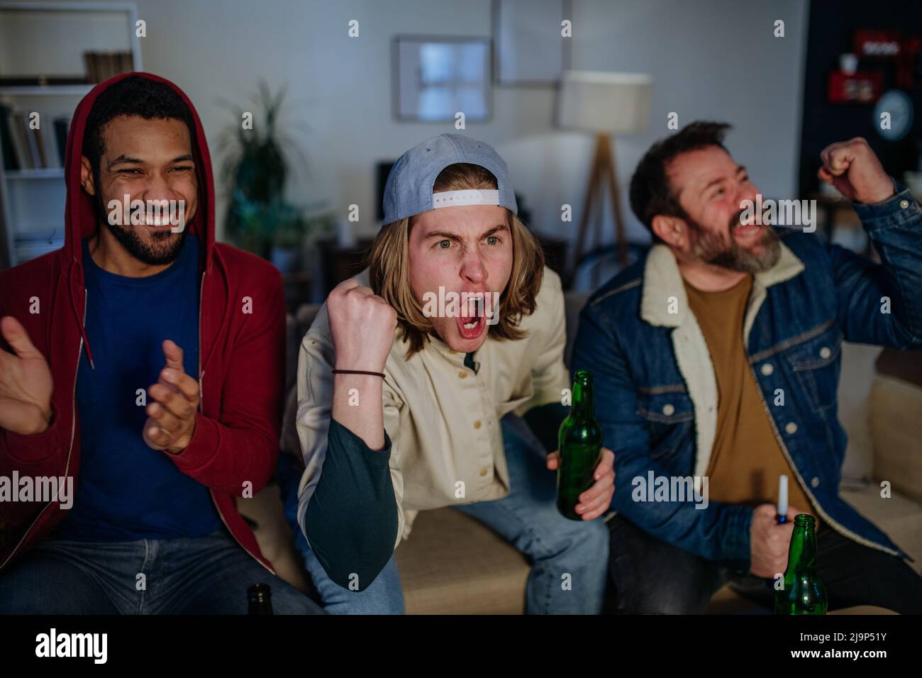 Happy football fans friends watching football at home and celebrating ...