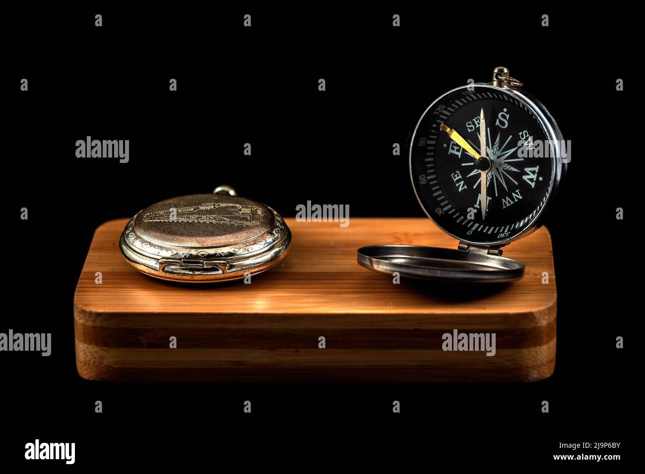 antique compass and pocket watch on wood with black background. studio ...