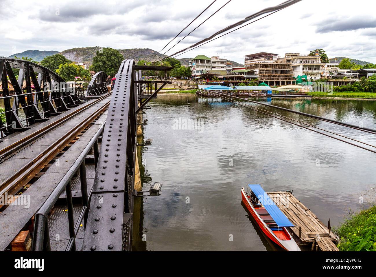 Tourists walk across the famous bridge over the River Kwai and a speed ...