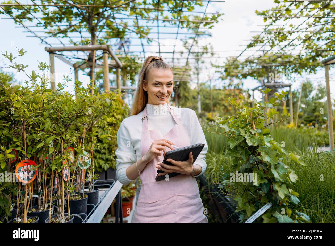 Female florist holding tablet. Owner of garden centre standing a ...