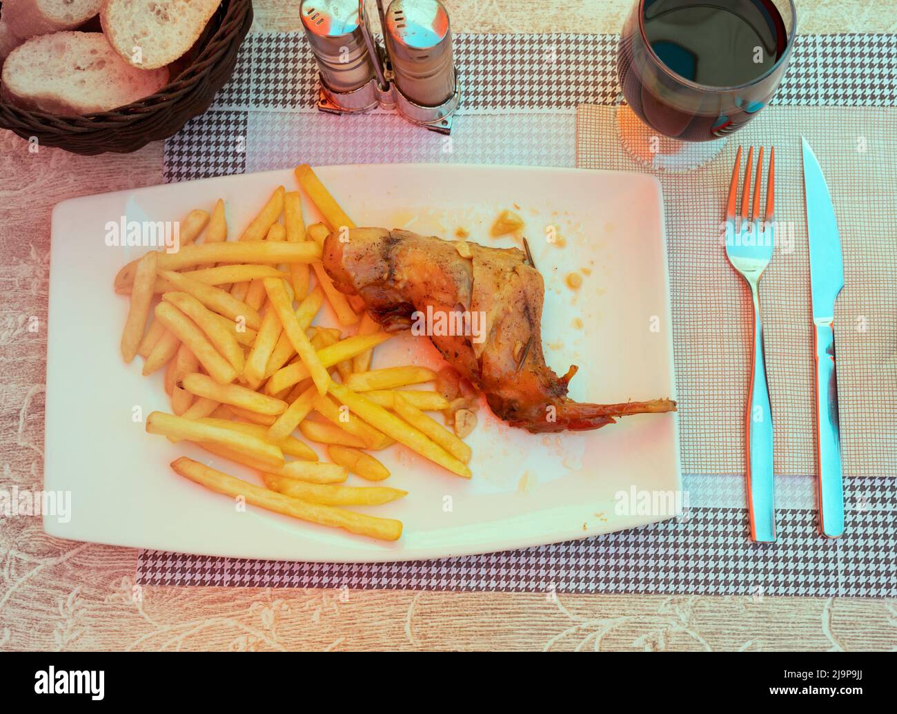 Baked rabbit leg served with french fries on plate Stock Photo - Alamy