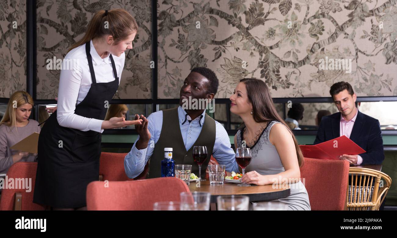 Couple talking with waitress in restaurant Stock Photo - Alamy