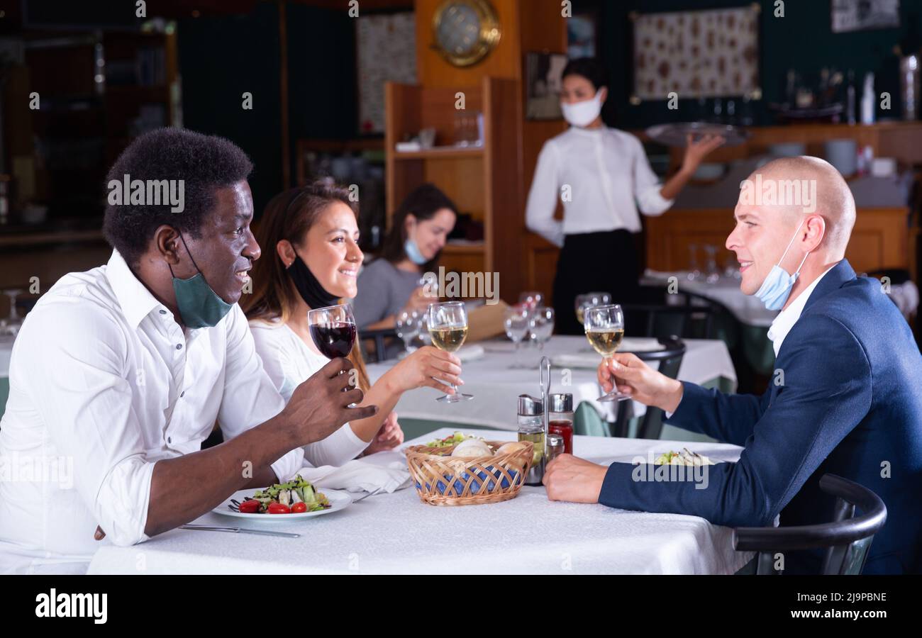 Cheerful people in masks having dinner in restaurant Stock Photo - Alamy