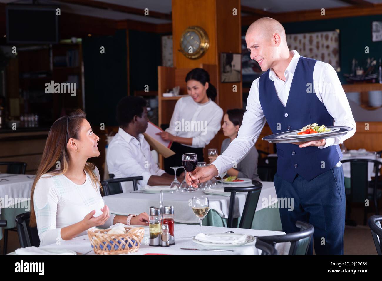 positive male waiter serving order to woman in restaurante Stock Photo ...