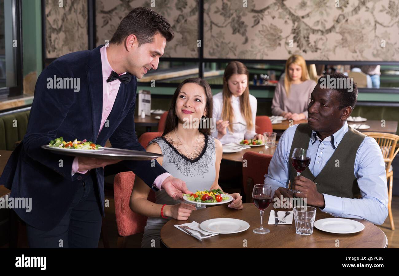 Waiter serving couple in restaurant Stock Photo - Alamy