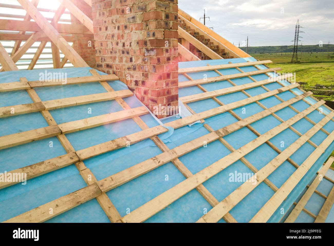 Aerial view of a brick house with wooden roof frame under construction ...