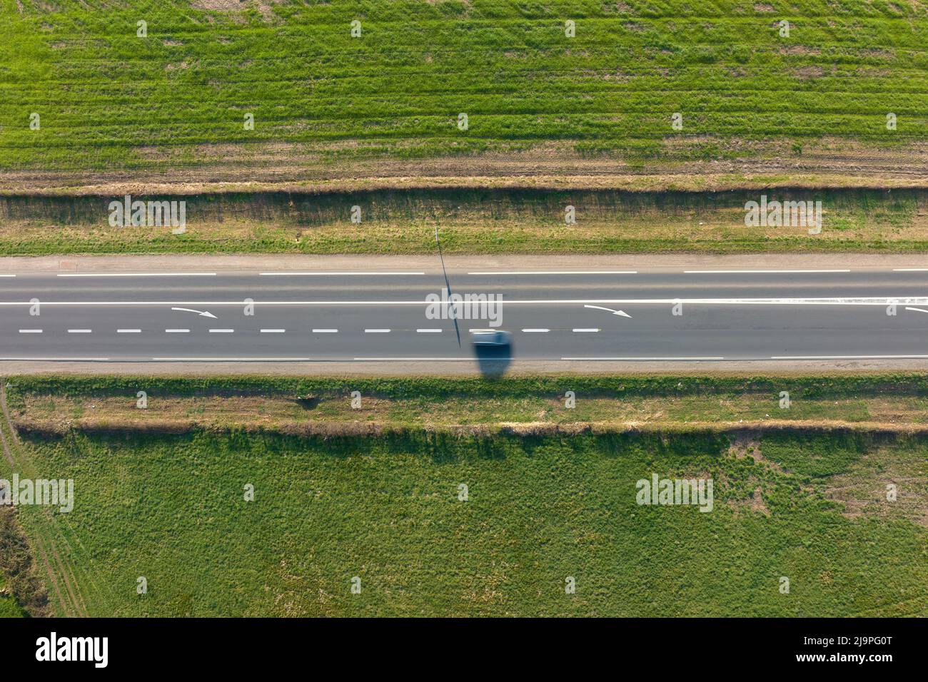 Aerial view of intercity road between green agricultural fields with ...