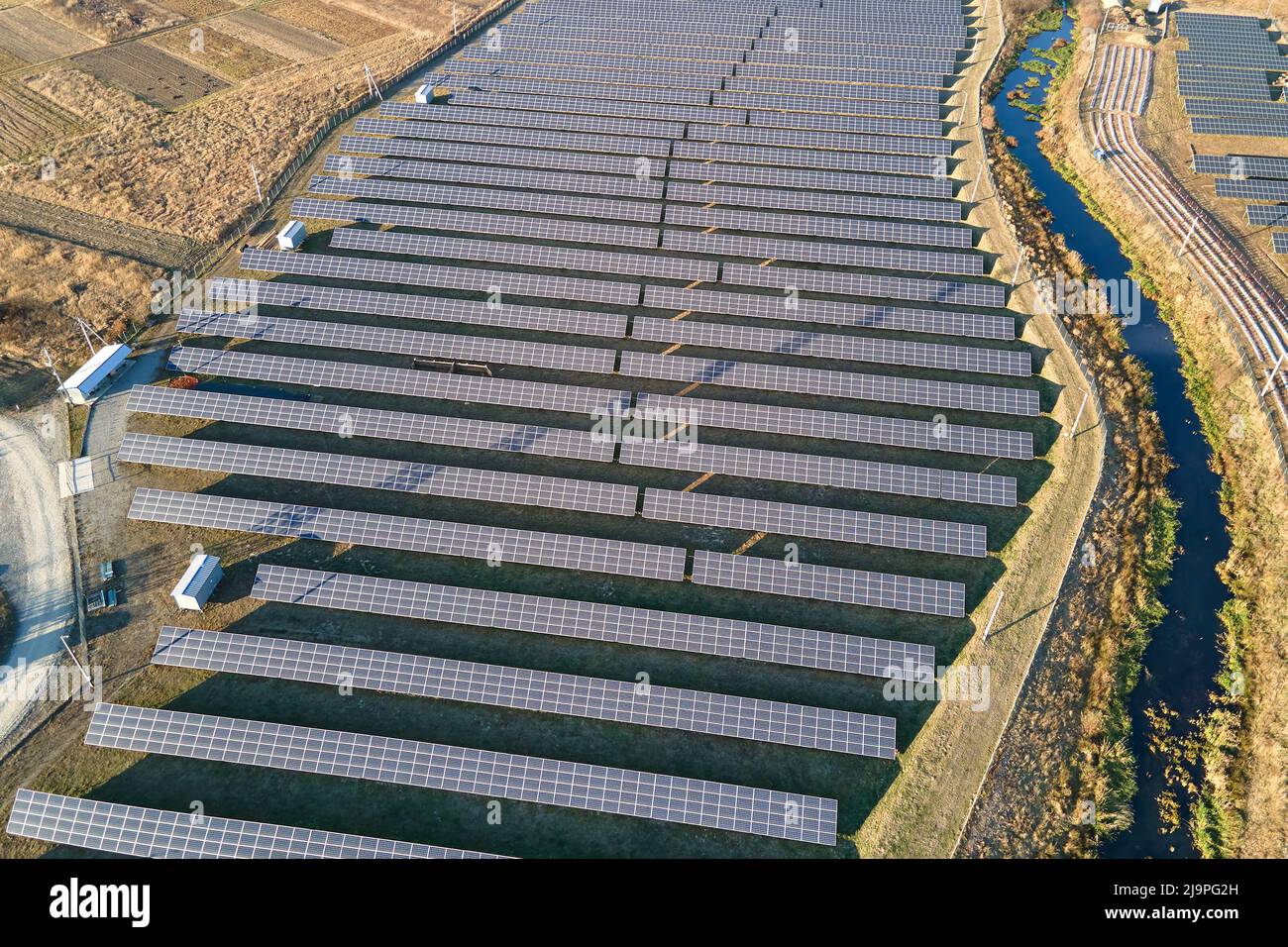 Aerial view of large sustainable electrical power plant with rows of solar photovoltaic panels ...