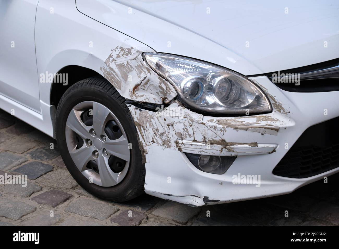 Dented car with damaged fender parked on city street side. Road safety ...
