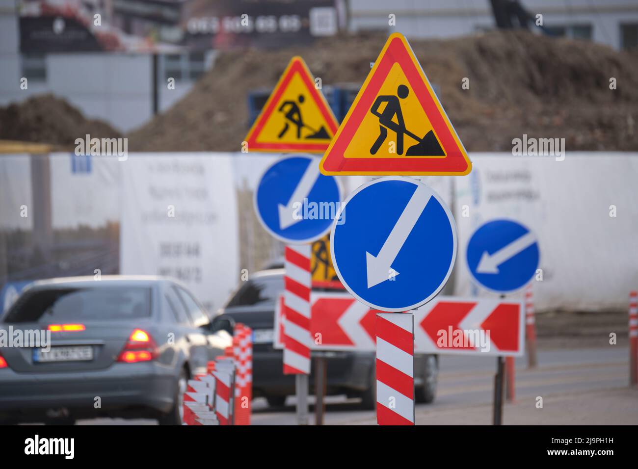 Roadworks warning traffic signs of construction work on city street and slowly moving cars Stock ...