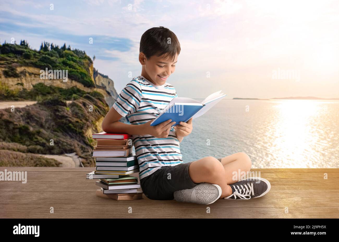 Cute little boy reading interesting books at resort Stock Photo - Alamy