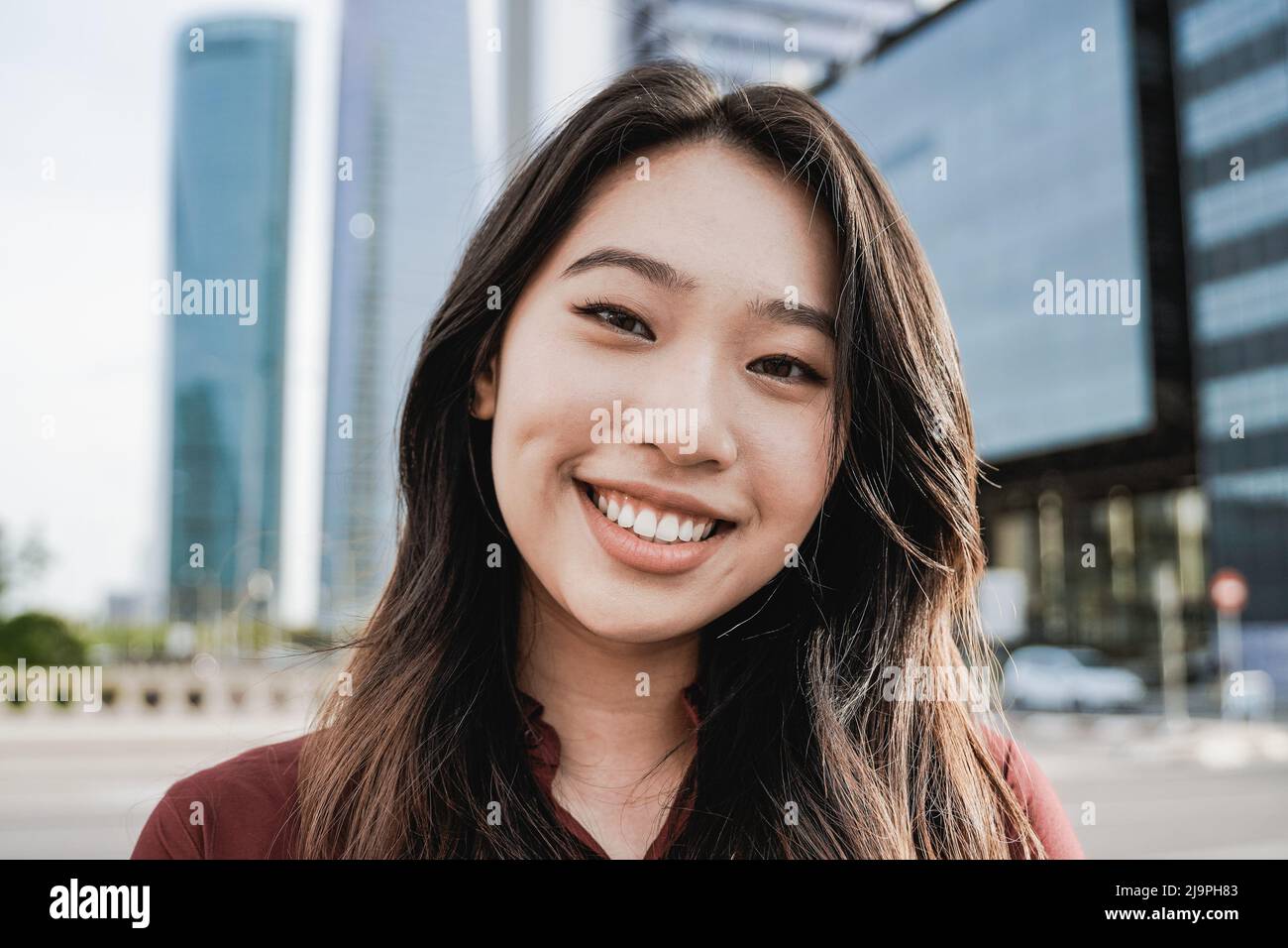 Asian business woman looking at camera outdoor with office buildings on ...
