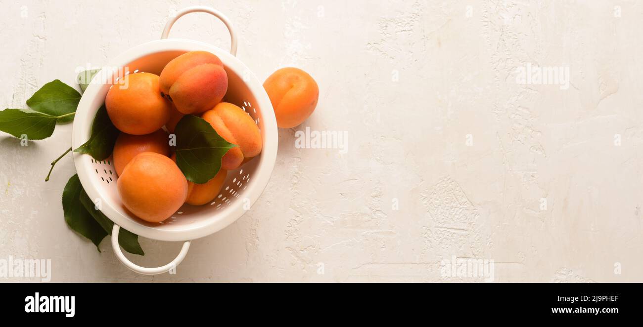 Colander of tasty ripe apricots on light background with space for text ...