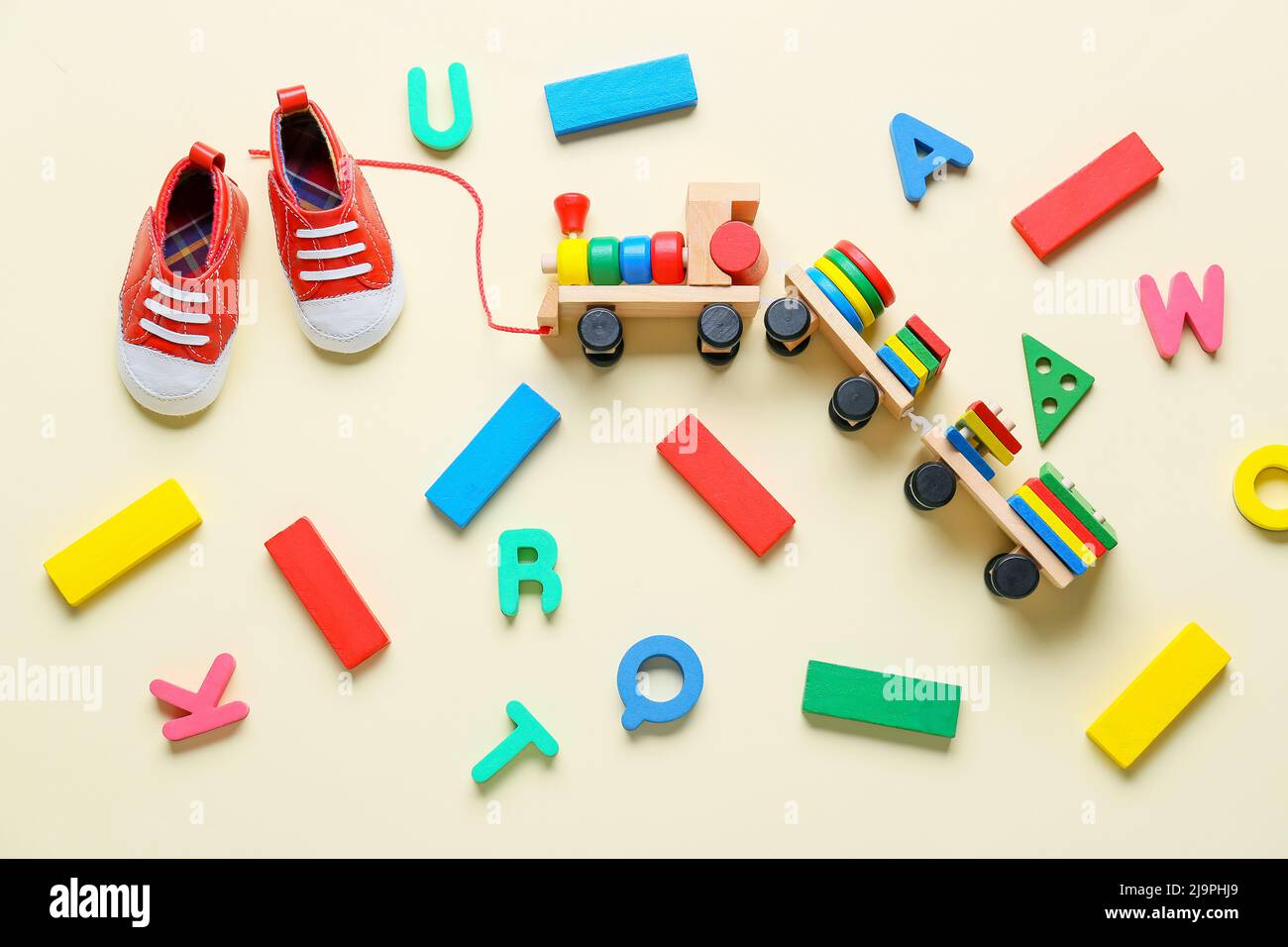 Toy train with building blocks, letters and booties on beige background ...