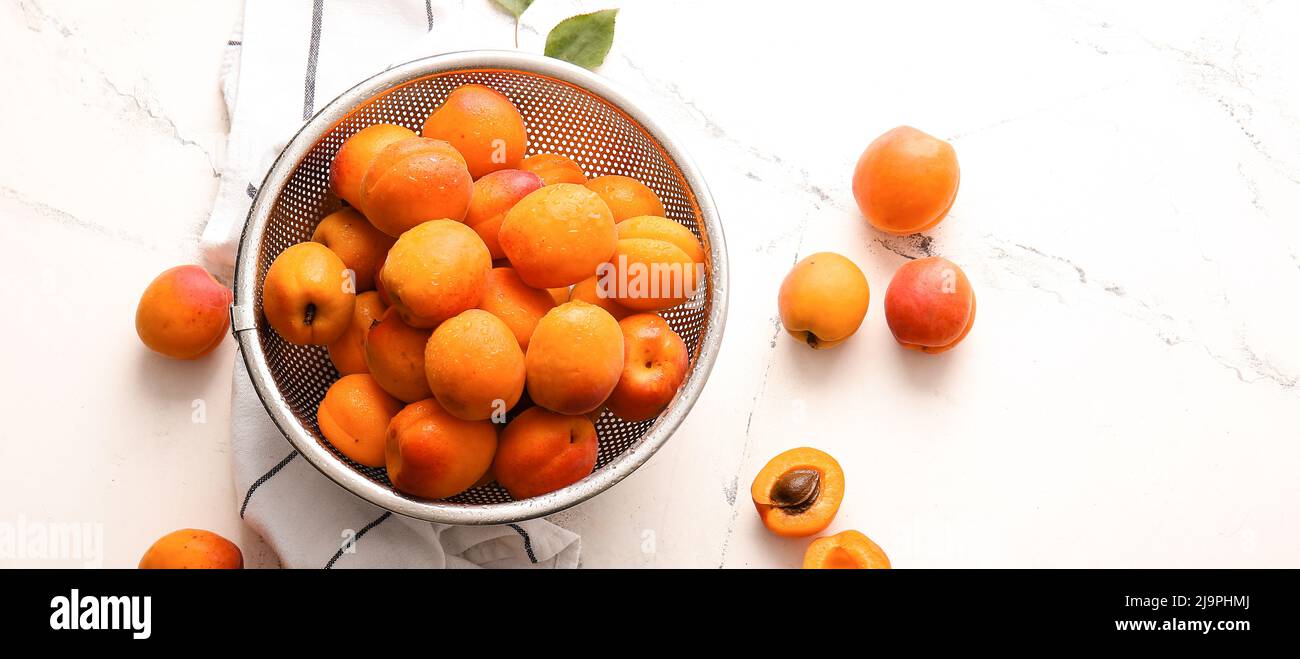 Colander with tasty ripe apricots on light background, top view Stock ...