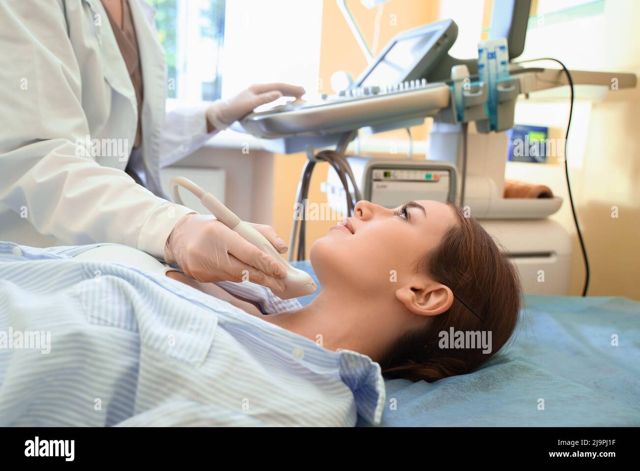 Young woman getting thyroid ultrasound examination in modern clinic ...