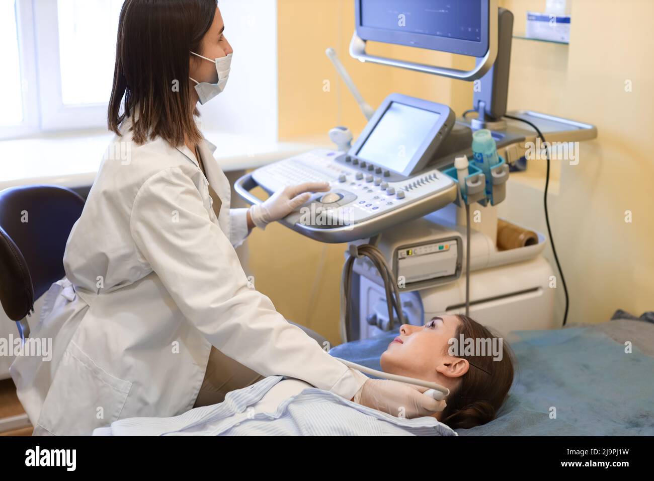 Young woman getting thyroid ultrasound examination in modern clinic ...