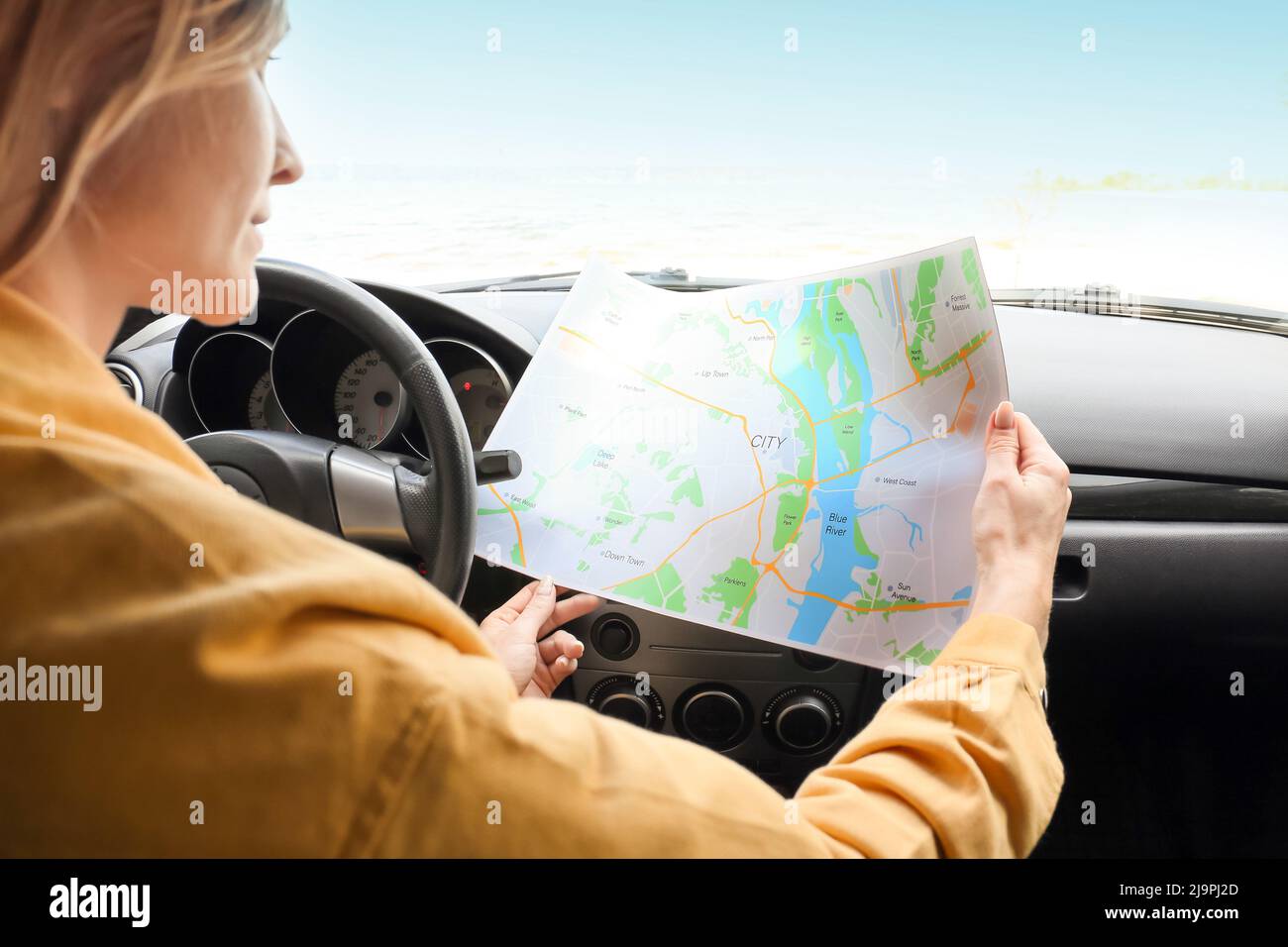 Female driver with city map in car Stock Photo - Alamy