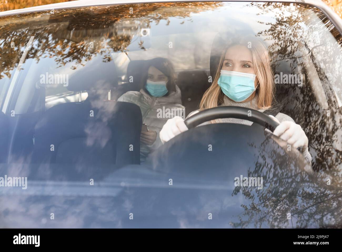 Female driver and passenger wearing medical masks in car Stock Photo ...