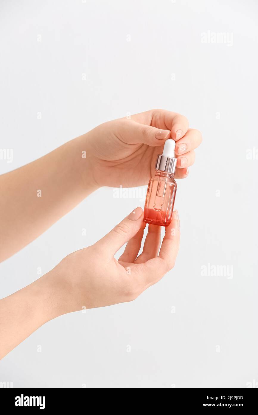 Female hands with bottle of serum isolated on white background, closeup ...