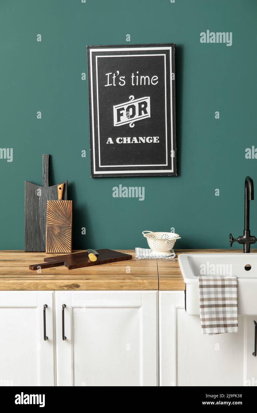 Cutting boards with knife and colander on counter near green wall Stock ...