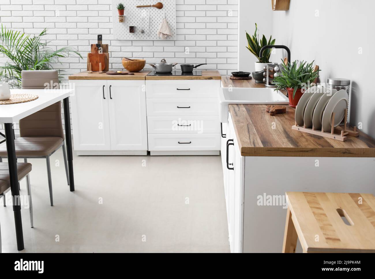 Interior of light kitchen with dining table, counters and utensils ...
