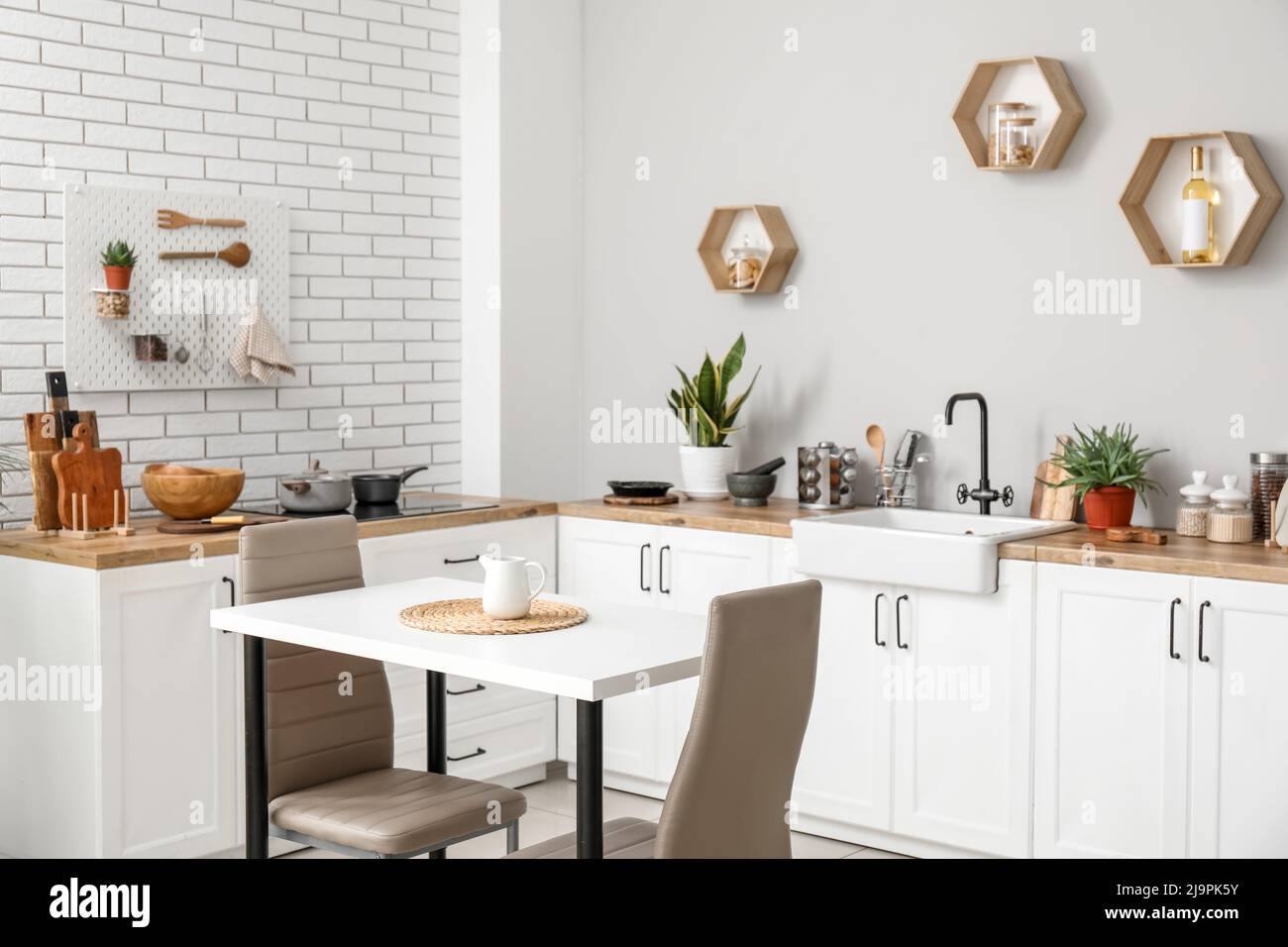 Interior of light kitchen with dining table, counters and utensils ...