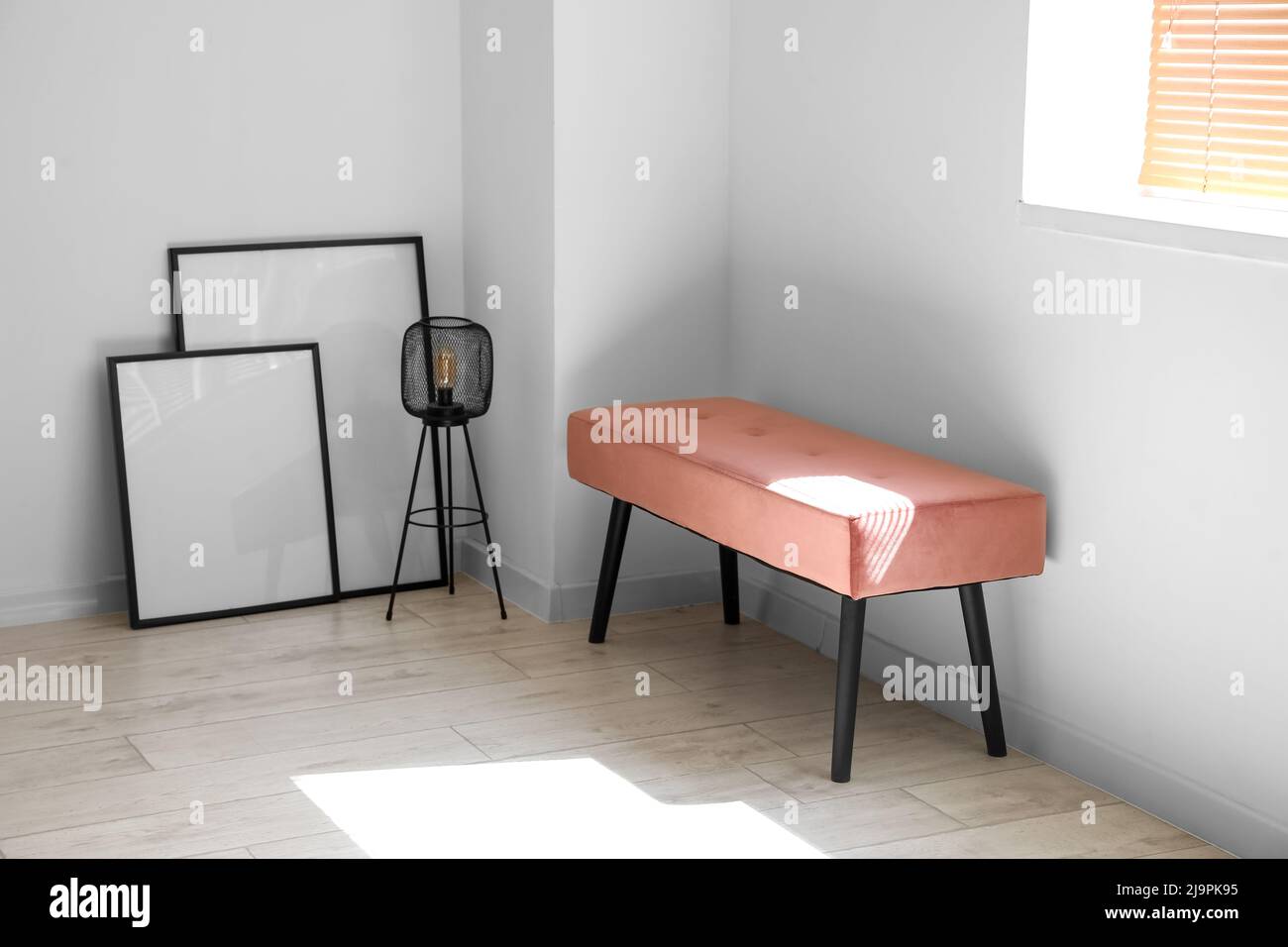Pink bench with lamp and blank frames in light room Stock Photo - Alamy