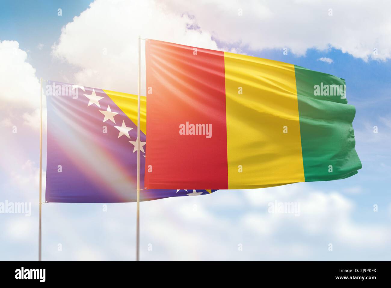 Sunny blue sky and flags of guinea and bosnia Stock Photo - Alamy