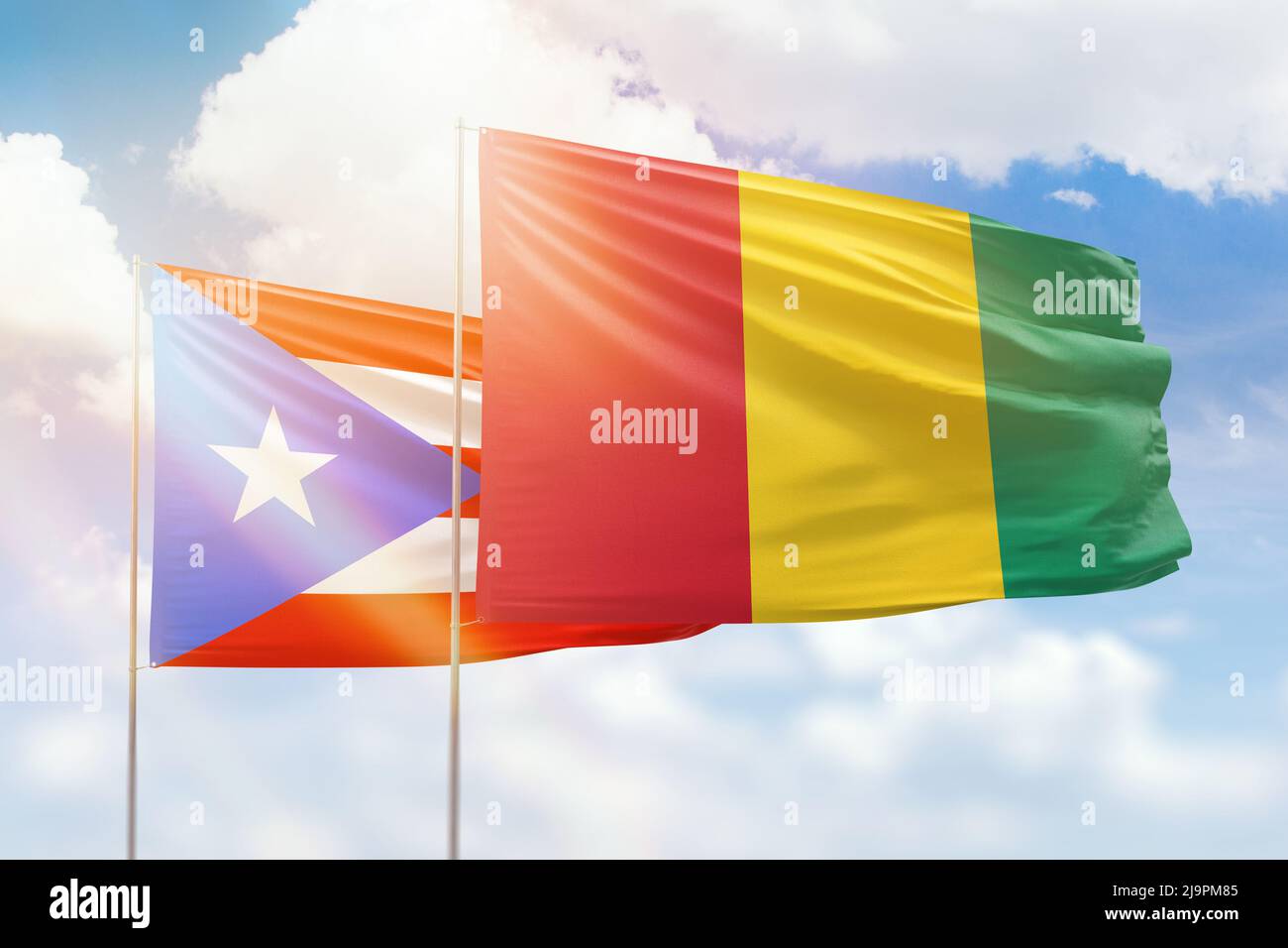 Sunny blue sky and flags of guinea and puerto rico Stock Photo - Alamy