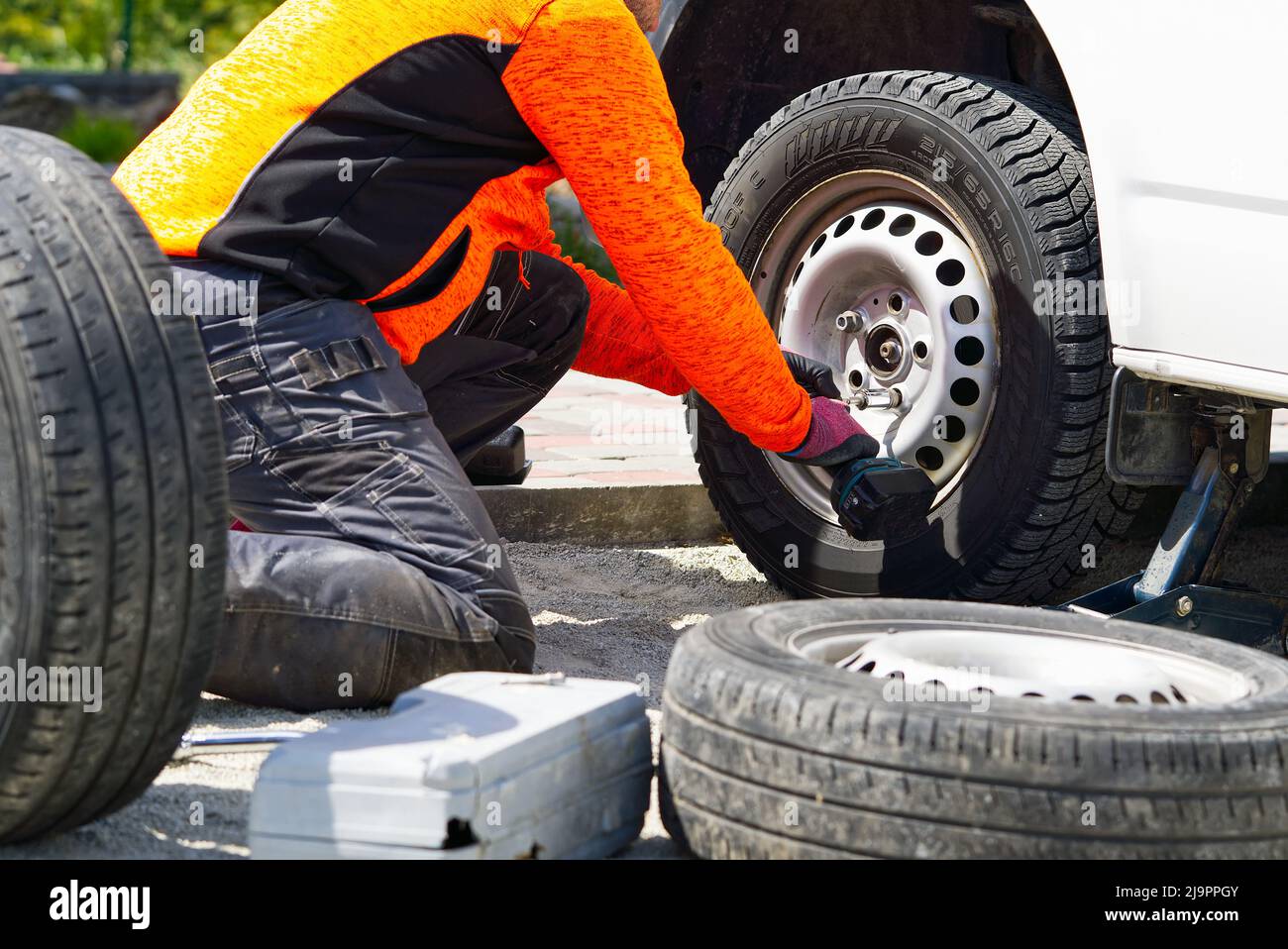 Mechanic changing car tire with tool. road help, changing and repairing ...