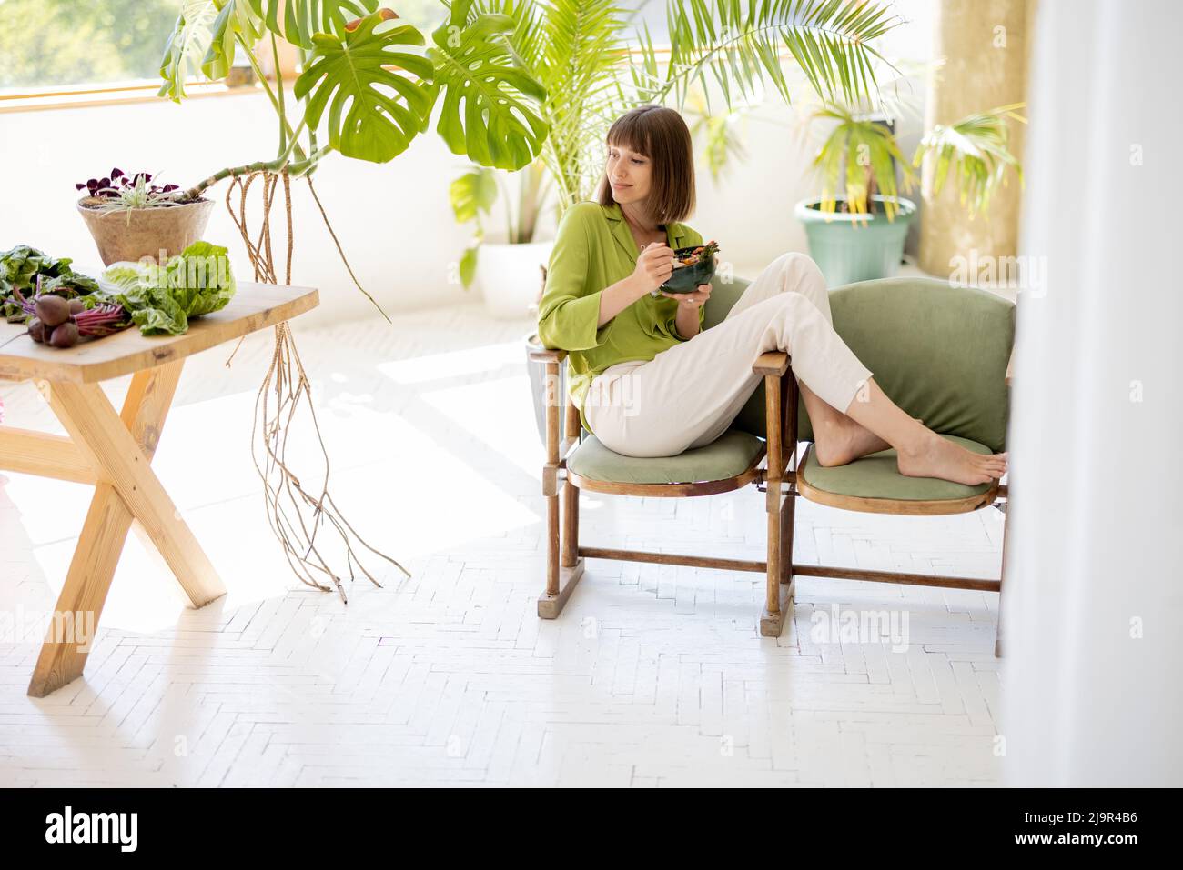 Relaxed woman with healthy food in the room with plants Stock Photo - Alamy