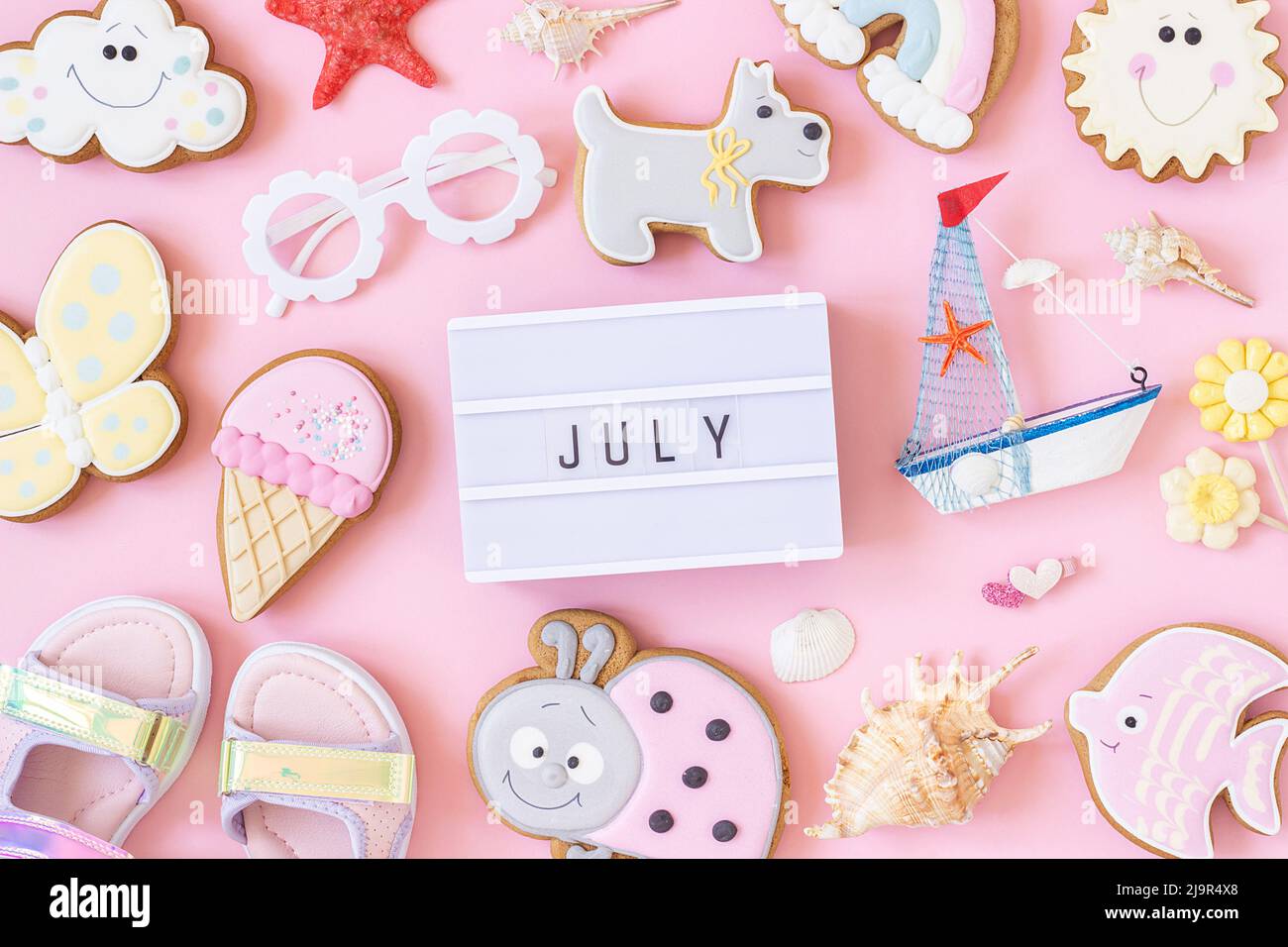 July text on lightbox and cute summer symbols on pink background. Top ...