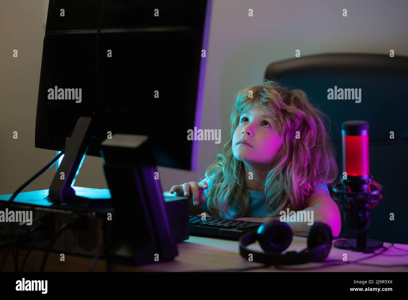 Child plays a video game on the pc computer screen. A pretty child ...