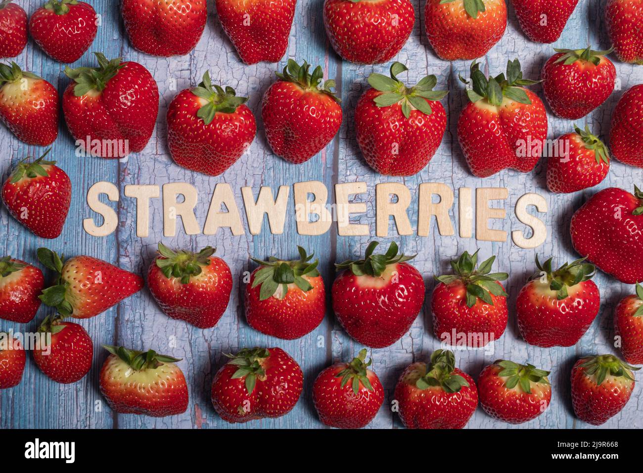 Many Red strawberries fruit on a blue wooden board and wooden ...