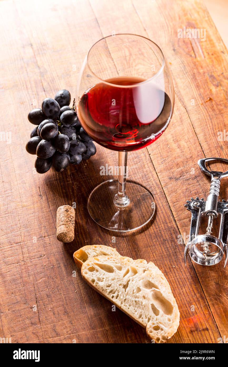 Pouring red wine glass against wooden background Stock Photo - Alamy
