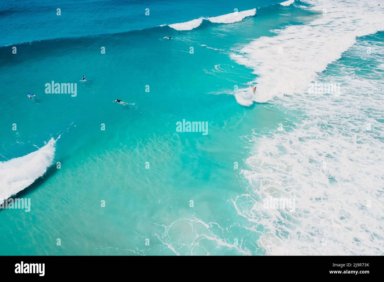 Surfers in blue transparent ocean and fun waves. Surfing in tropics ...