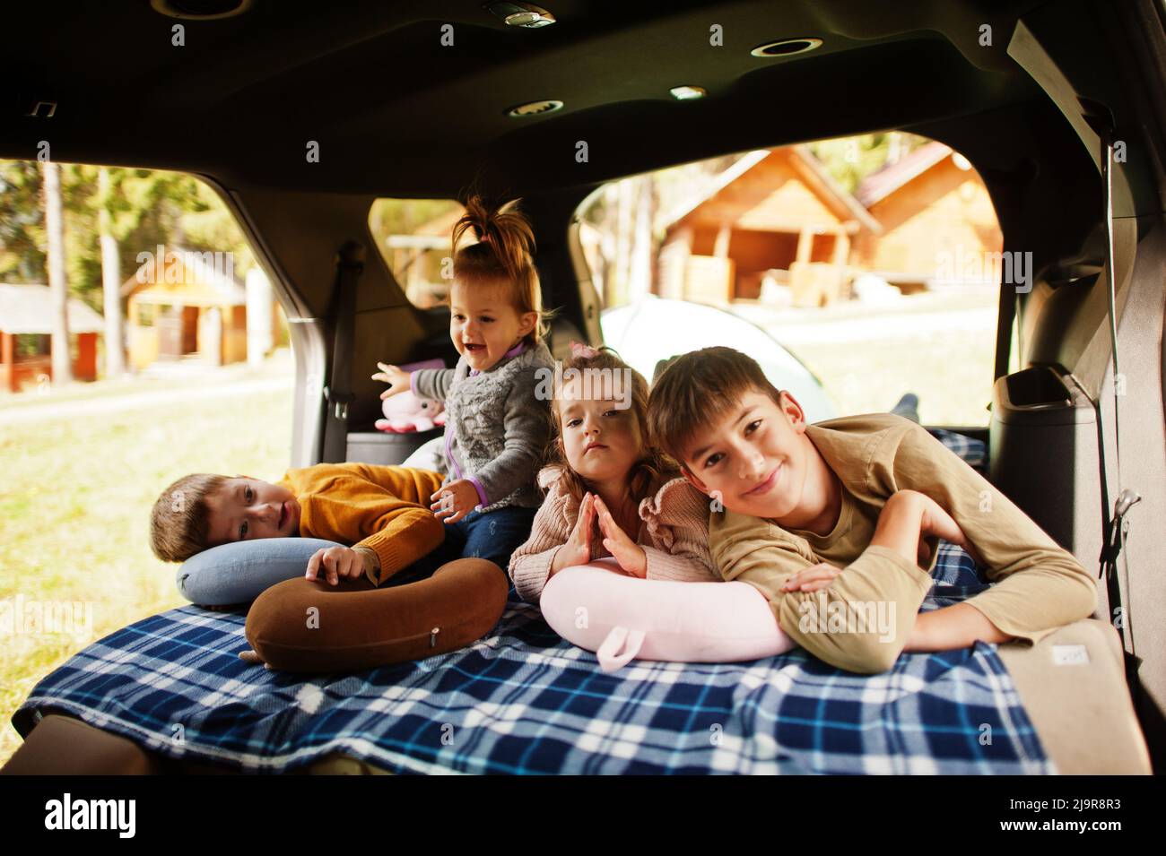 Family of four kids at vehicle interior. Children in trunk. Traveling ...
