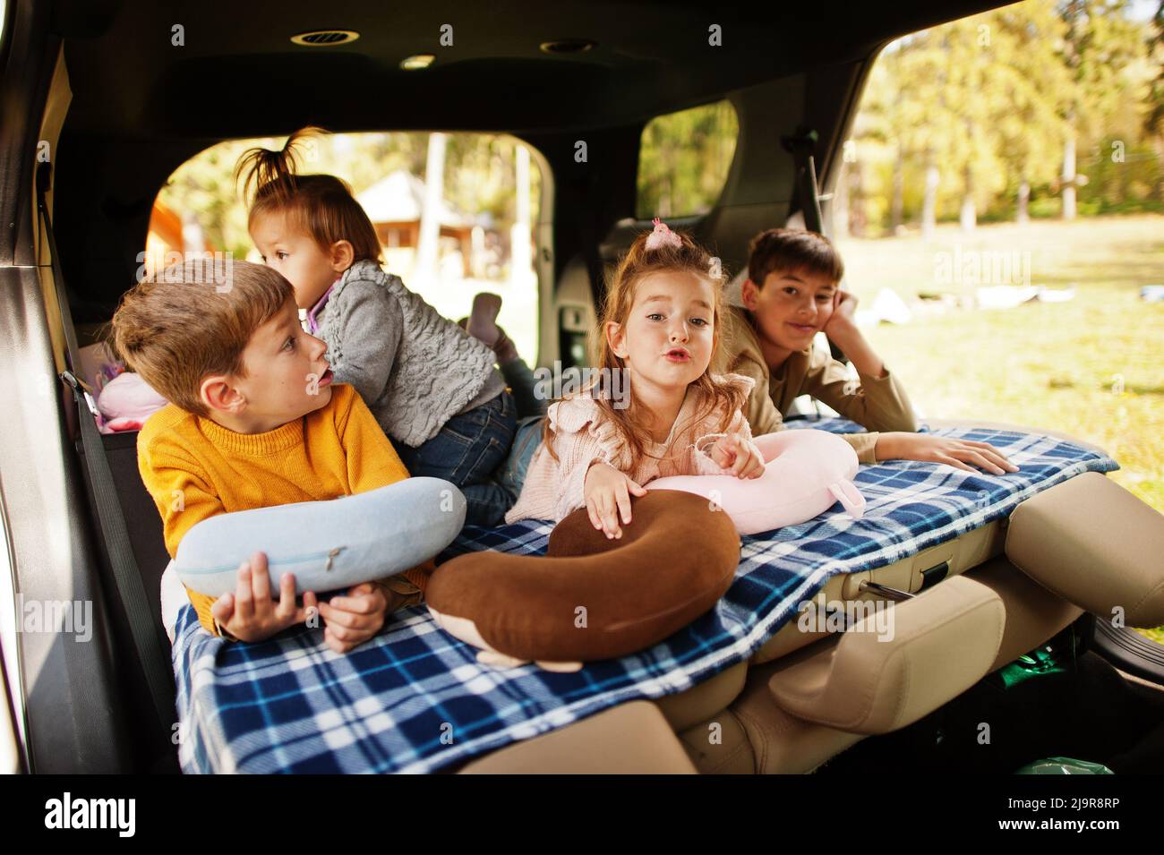 Family of four kids at vehicle interior. Children in trunk. Traveling ...