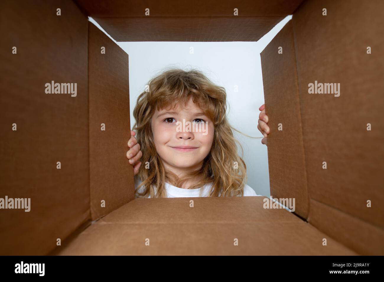 The surprised child unpacking, opening carton box and looking inside ...