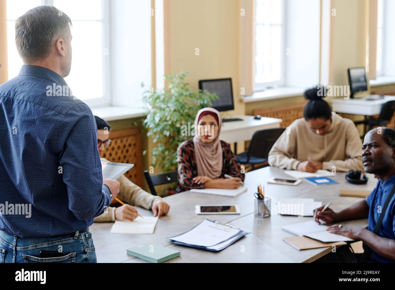 High angle shot of unrecognizable Caucasian man giving lessons for multi-ethnic group of ...