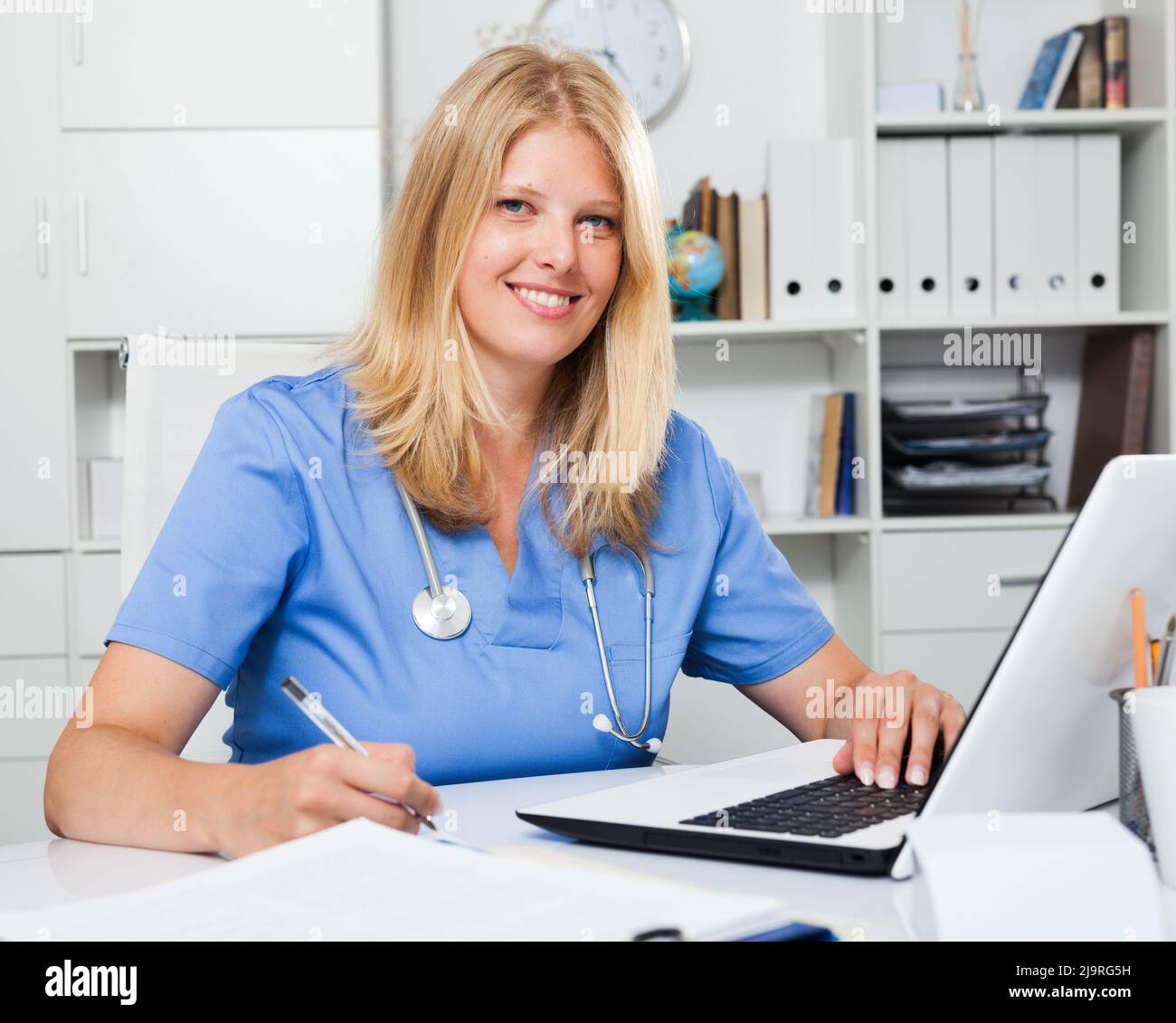 Doctor sitting at workplace with computer Stock Photo - Alamy