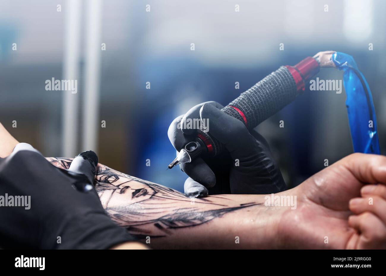Close up of a tattoo artist tattoos a black tattoo with paint, tattoo ...