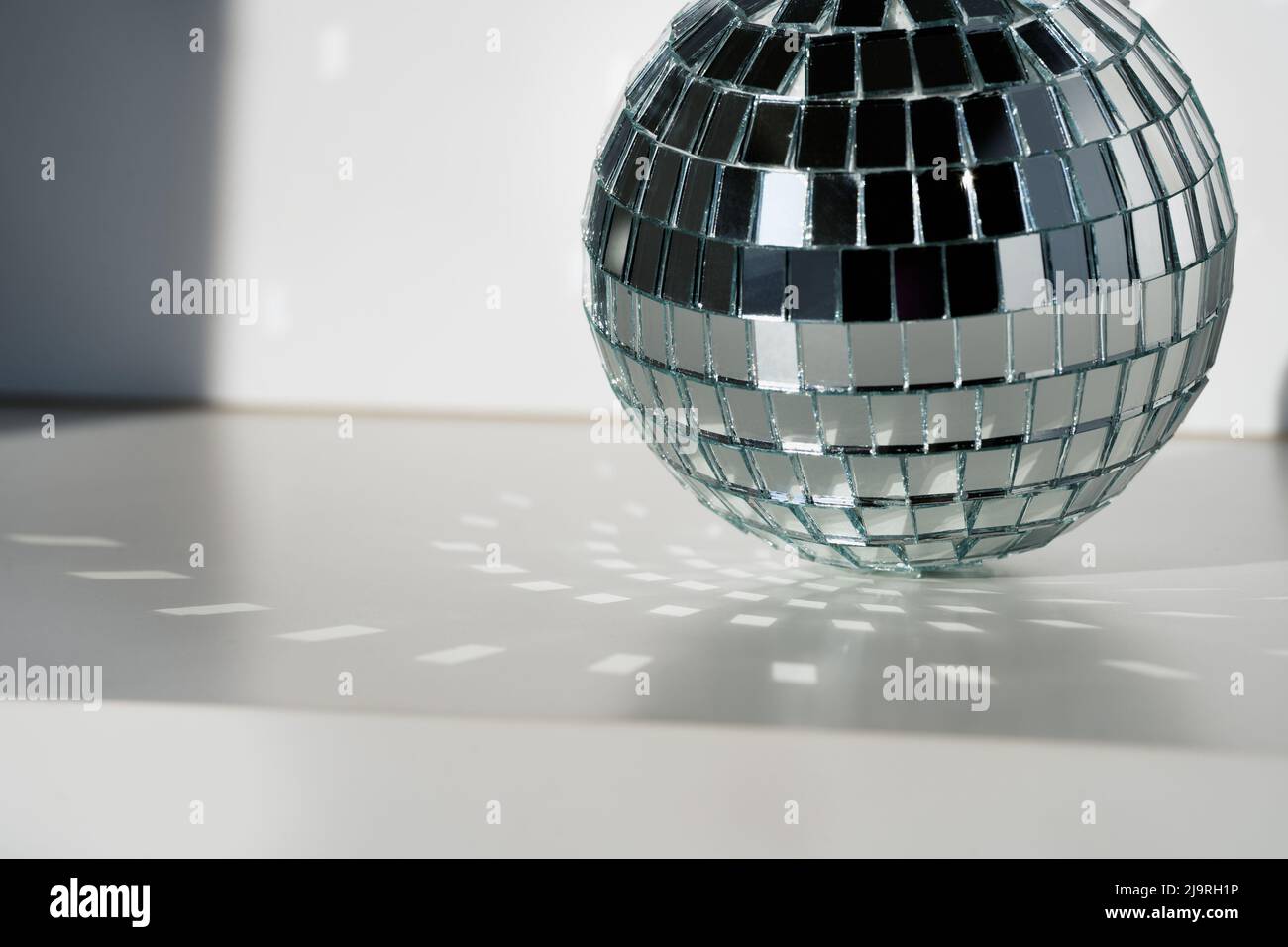 Macro disco ball in sunlight with sunbeam reflections on white ...