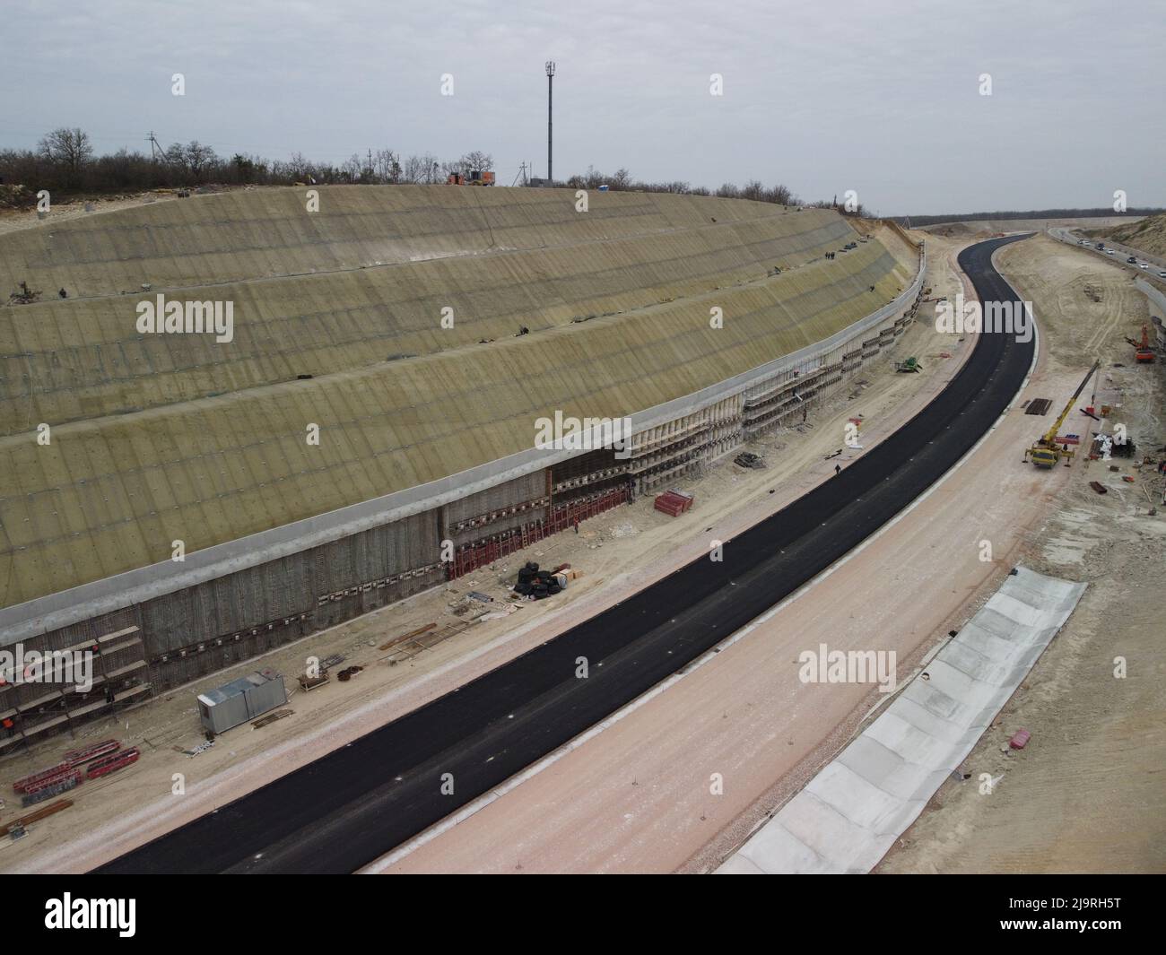Workers reinforce the slope over the new road. Road construction in ...