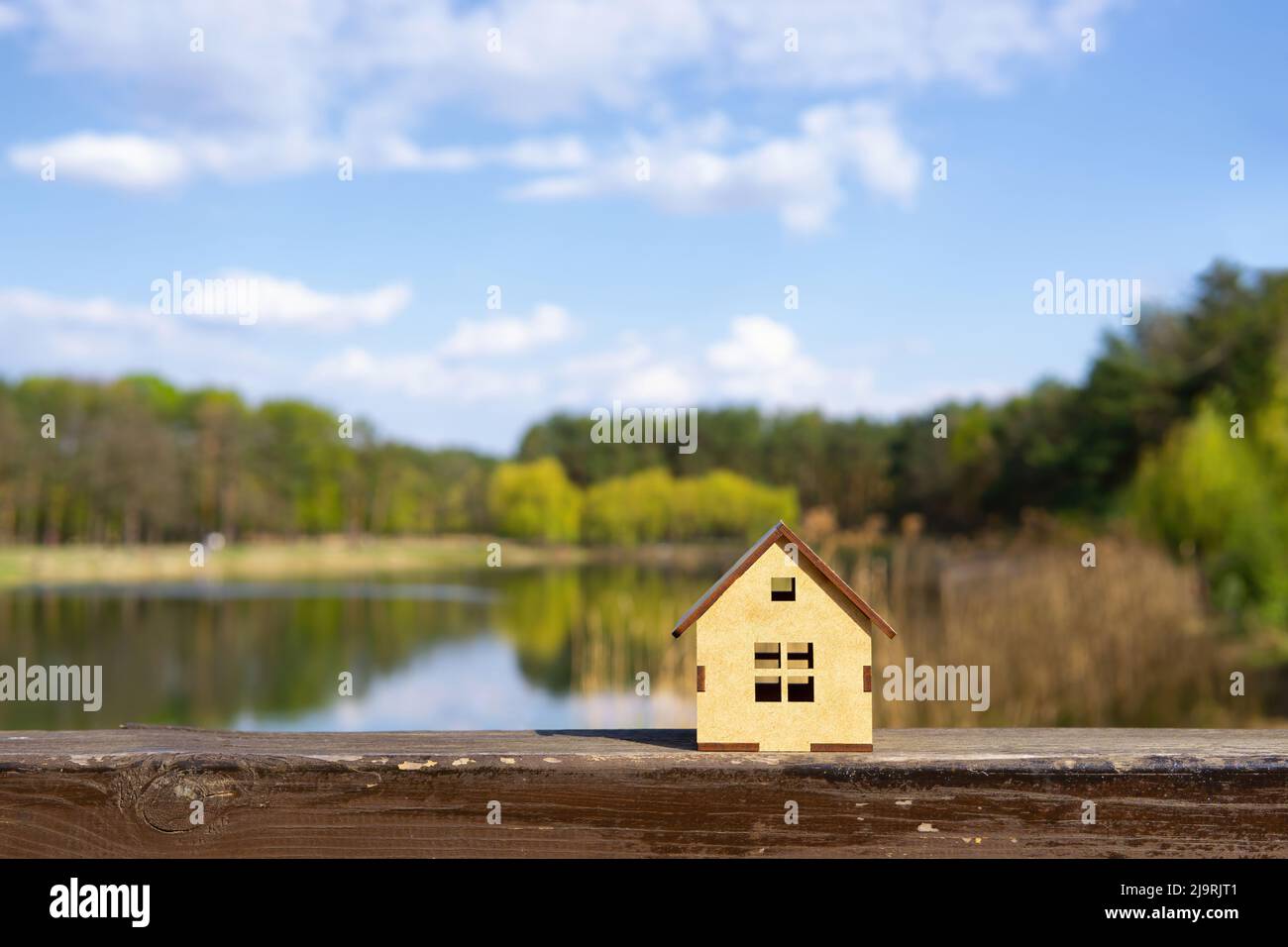 Miniature wooden cabin by against a beautiful lake landscape background ...