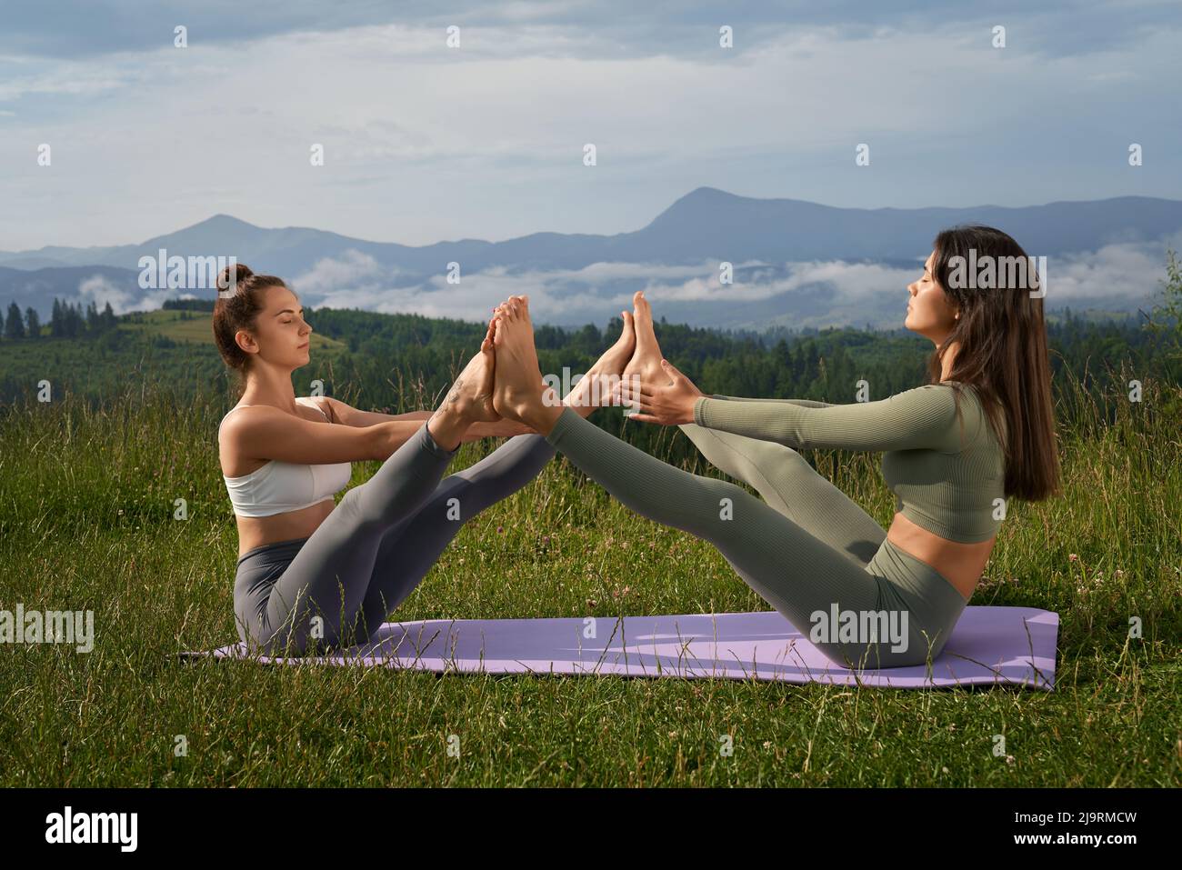 Side view of beautiful women holding legs together in asana and ...